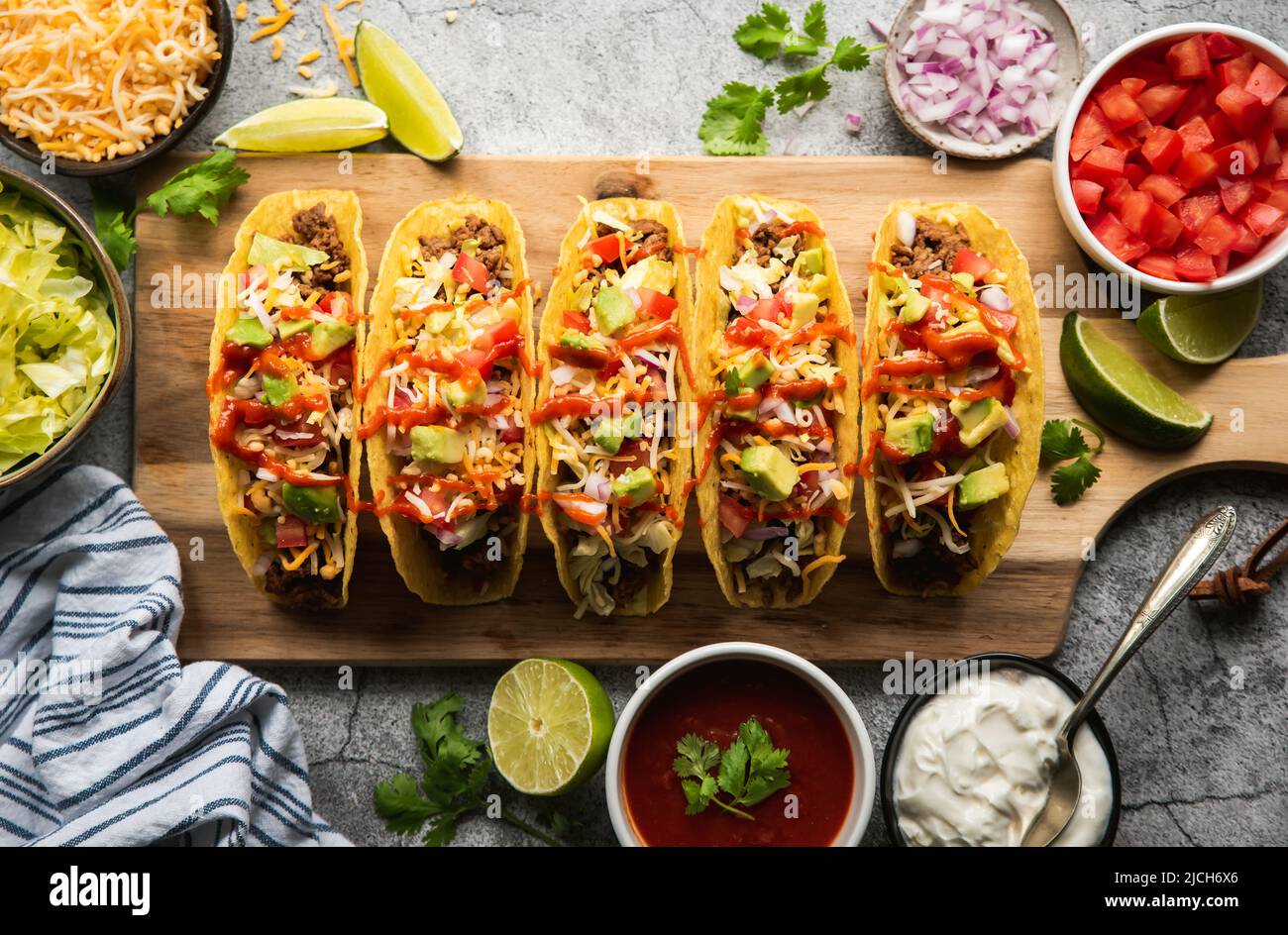 Hard shell tacos on wooden board with beef, lettuce, tomatoes, cheese ...