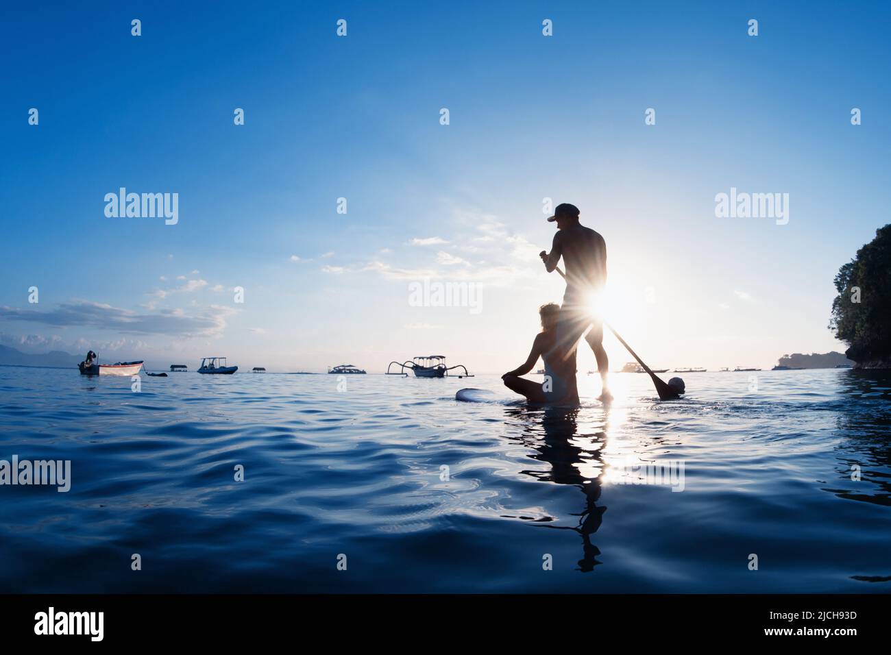 Young happy couple have fun on stand up paddleboard. Active paddle ...