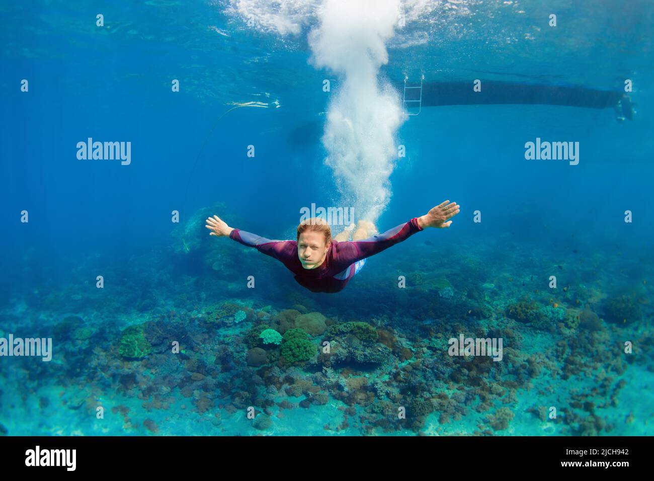 Active teenage man jump and dive underwater in tropical coral reef pool ...