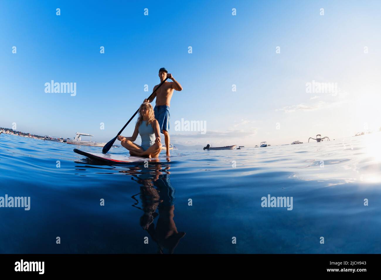 Young happy couple have fun on stand up paddleboard. Active paddle ...