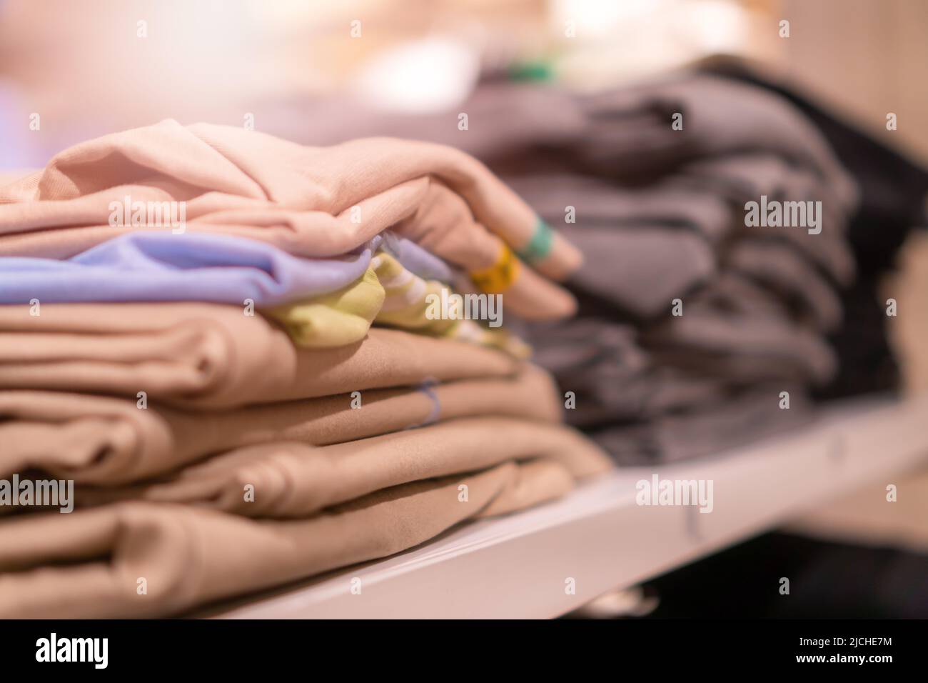 Selective close-up focus of a stack of light clothes on a shelf in a ...