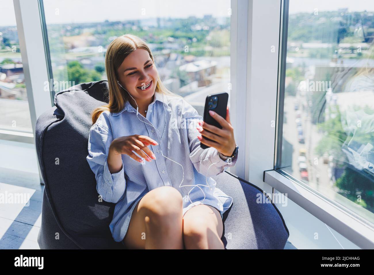 Woman in classic glasses listening to music with headphones from phone ...