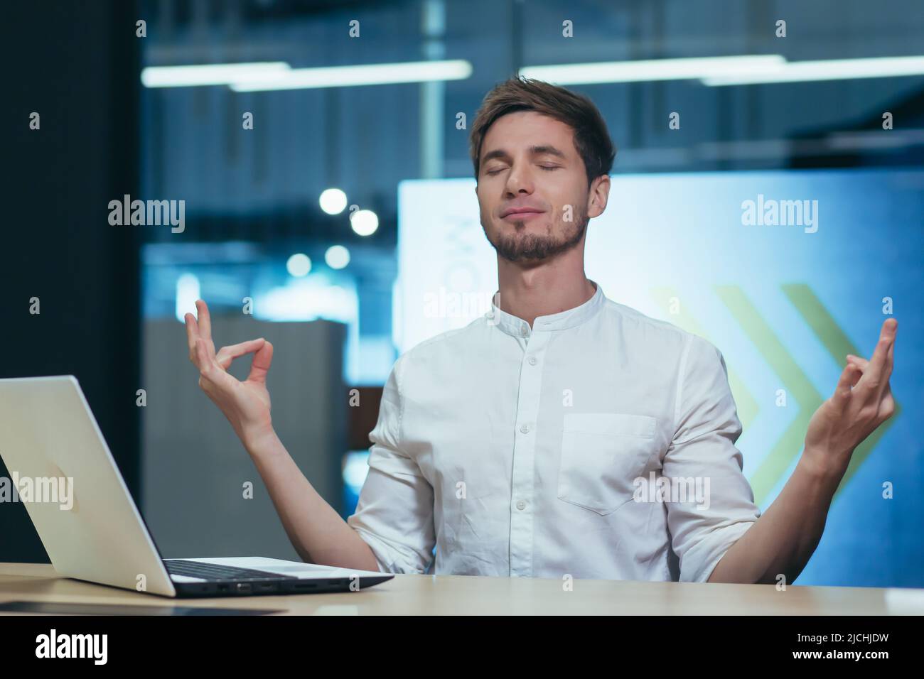 Business man working in a modern office, meditating and practicing yoga ...