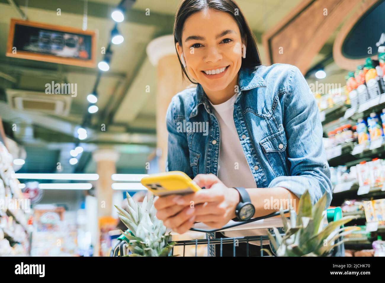 Portrait happy young woman shopping for groceries in supermarket ...
