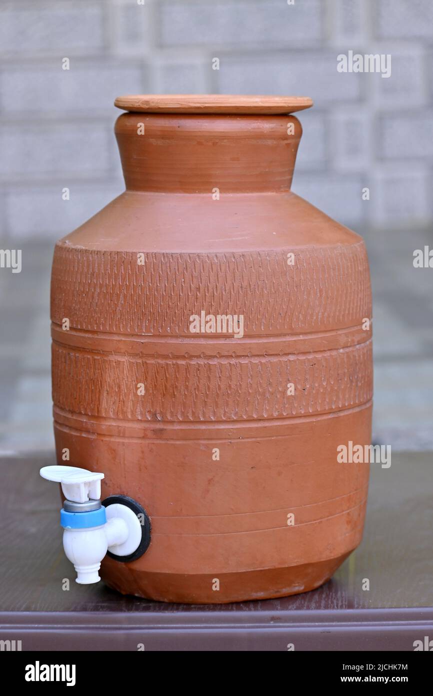 closeup the red brown earthen clay filter with blue white tap on the ...