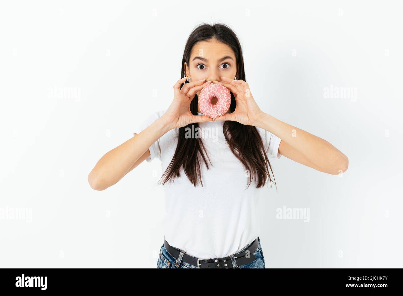 Surprised funny young woman holding donut like mouth standing on white ...
