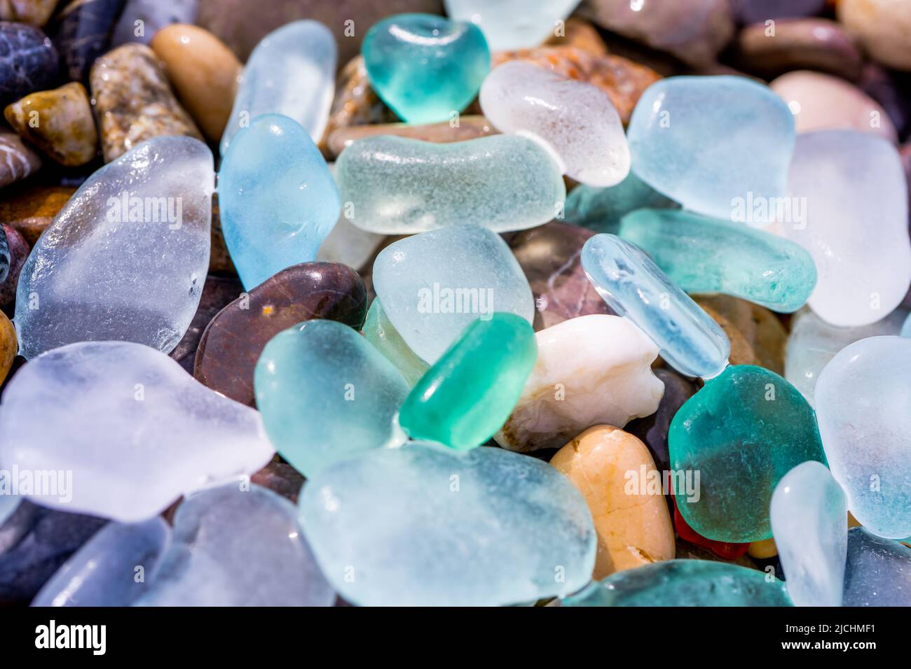 Natural polish textured sea glass and stones on the seashore. Azure ...