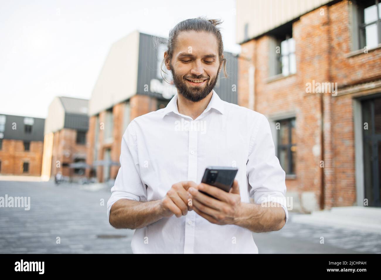 Handsome smiling business man with beard, in white shirt walks around ...