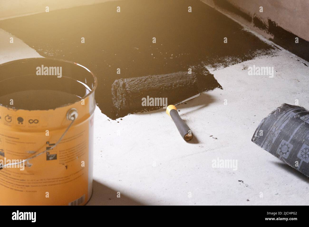 Applying hot resin to the floor for waterproofing, roller and bucket of ...