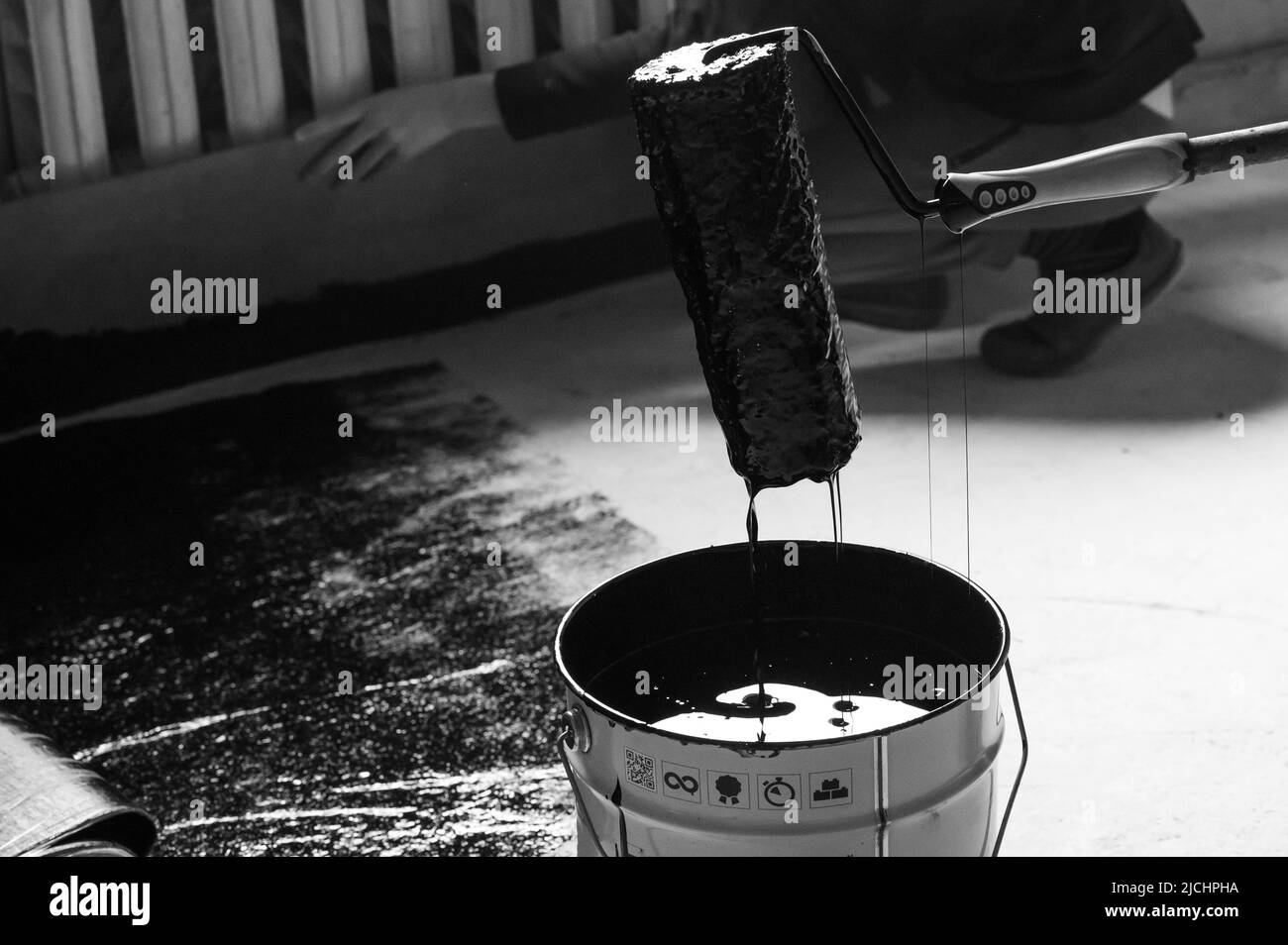 Applying hot resin to the floor for waterproofing, roller and bucket of ...