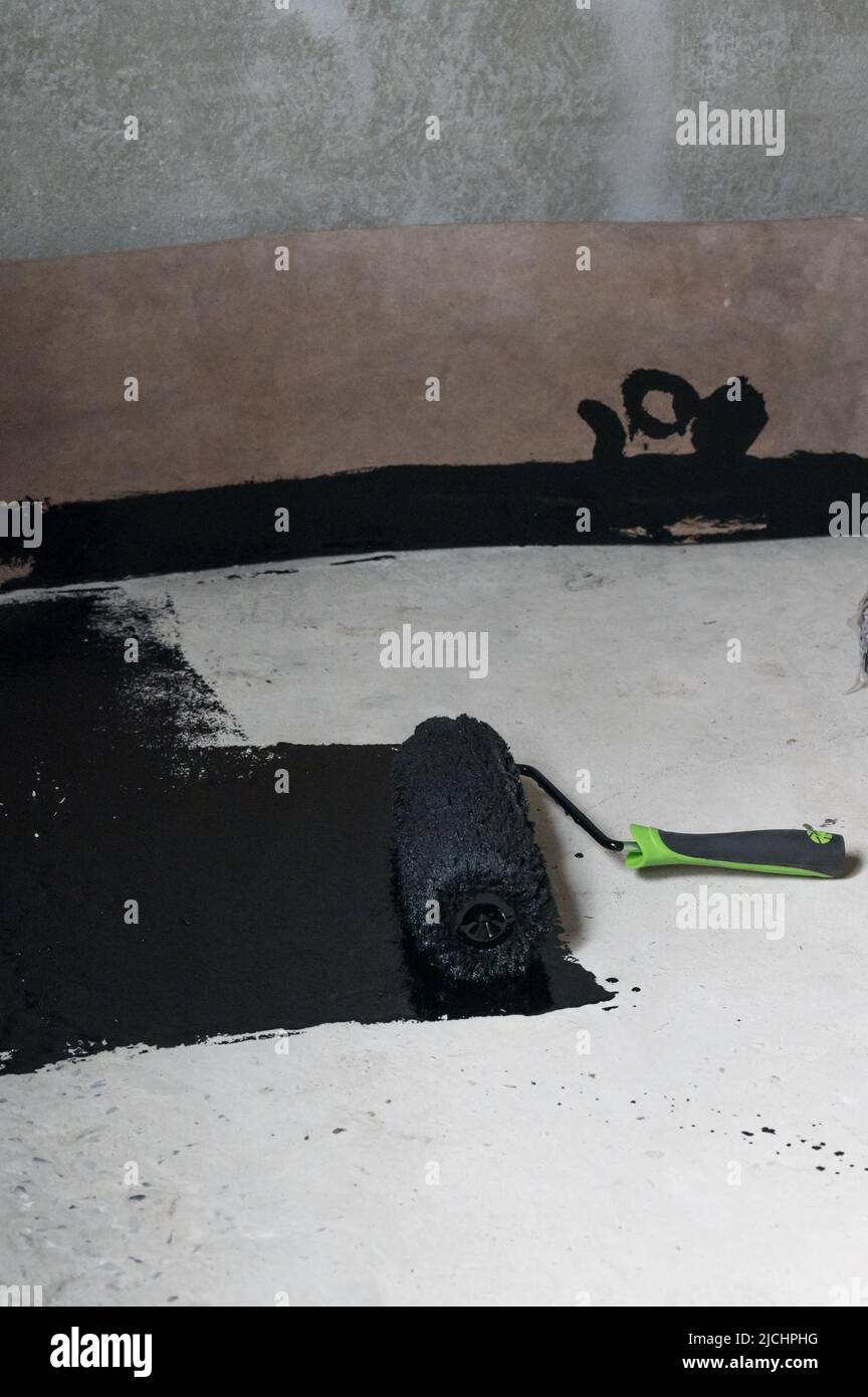 Waterproofing the floor in a private house, applying liquid resin to ...