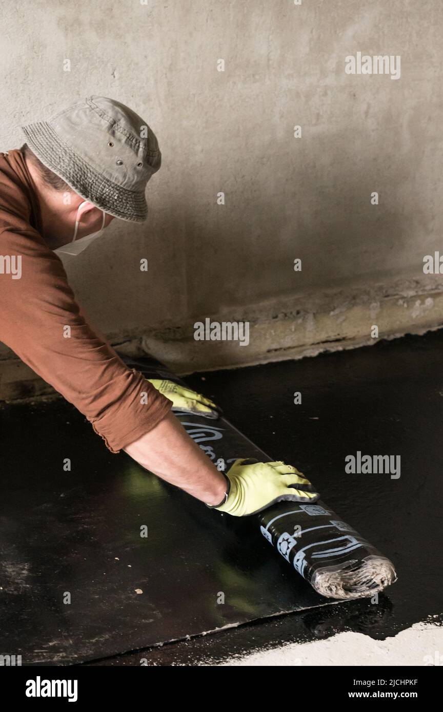The worker untwists the roll of waterproofing and fastens it to the ...