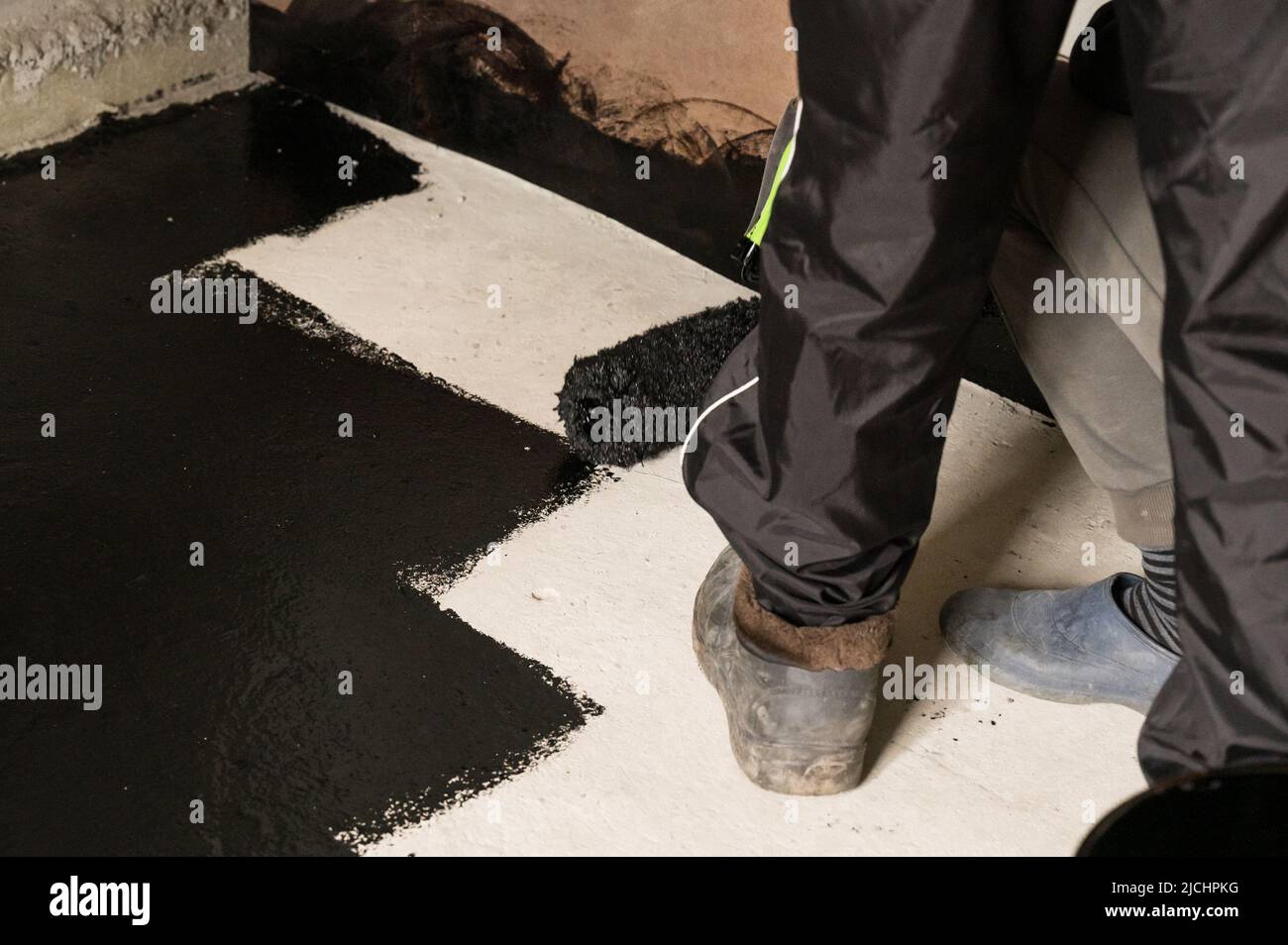 Waterproofing the floor in a private house, applying liquid resin to ...
