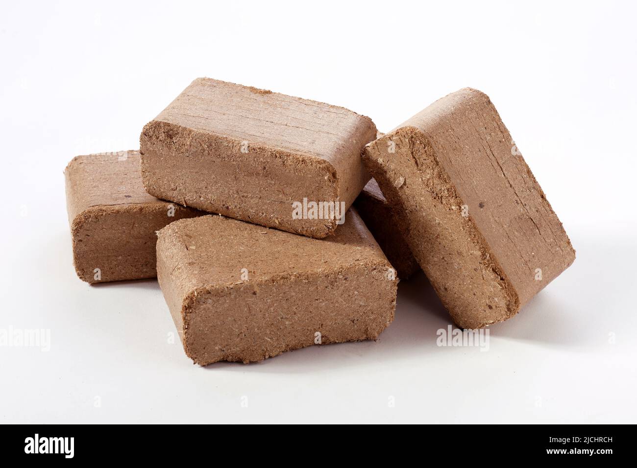 Stack of solid peat fuel biomass briquettes arranged against white ...