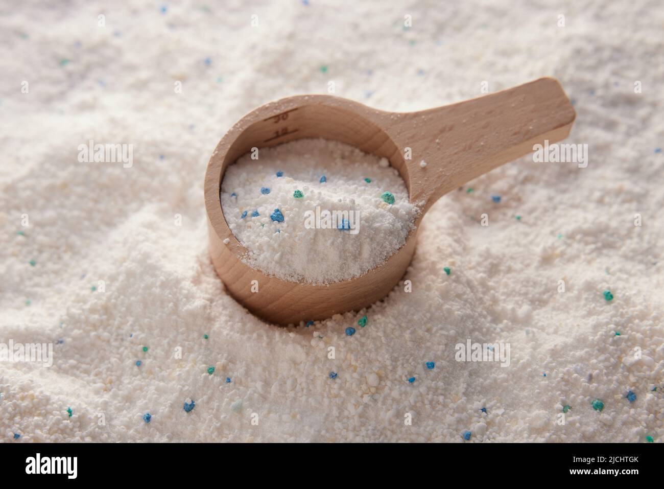 From above of wooden measuring cup with laundry detergent placed on ...
