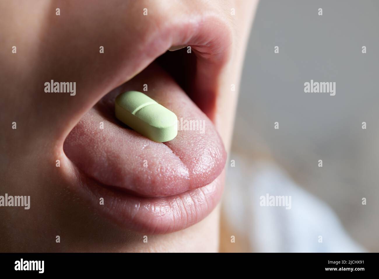 Close up of face of young woman taking drug. The drug addict is ...