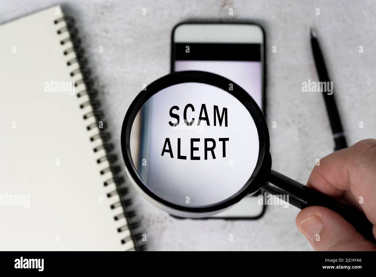 A man's hand holds a black magnifying glass by the handle on a ...