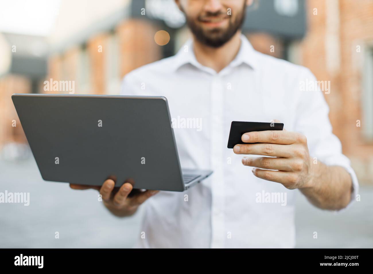 Focus on laptop and bank card. Business trip concept. Handsome young ...