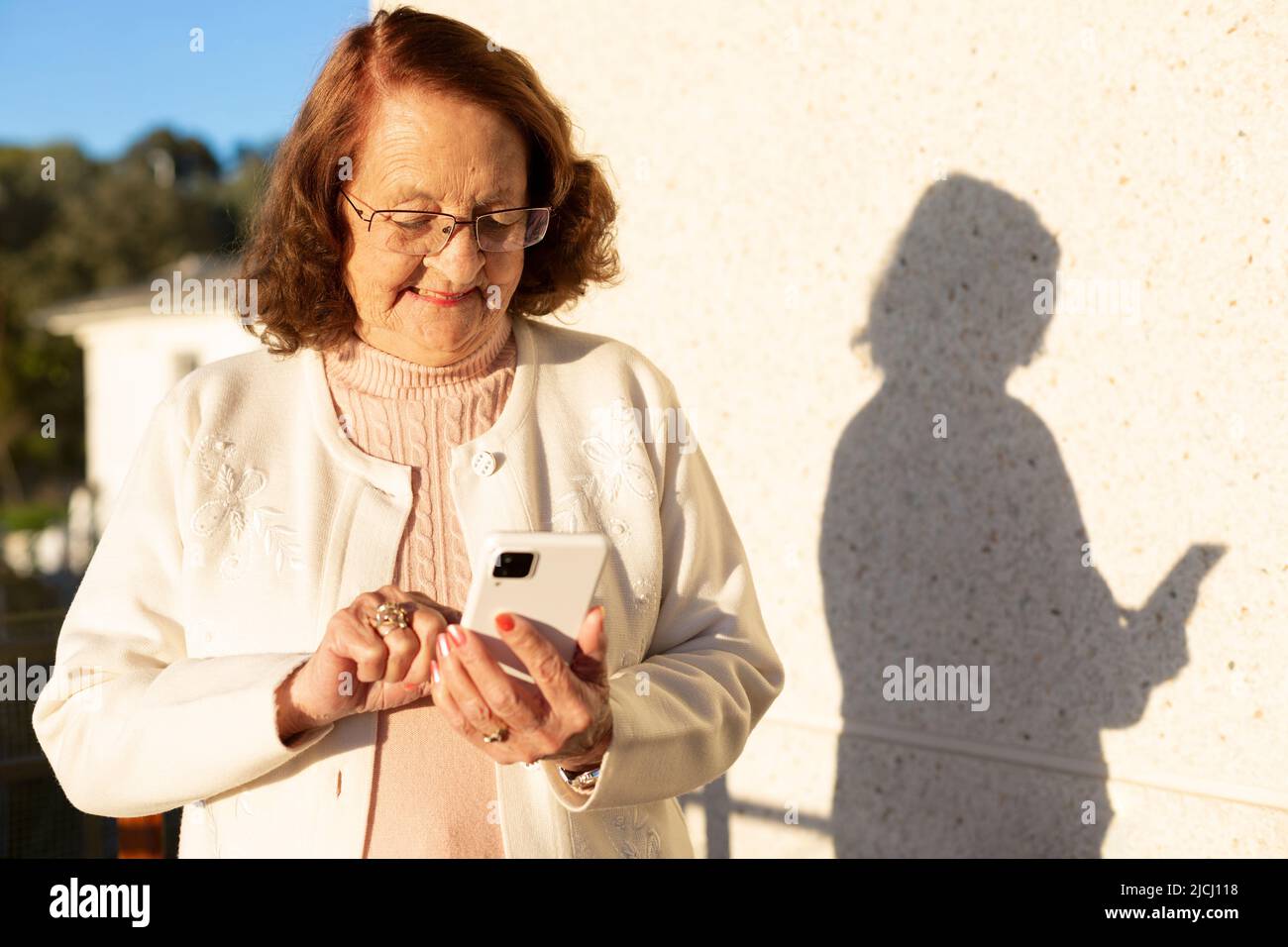 Old Caucasian woman using a smart phone outdoors. Concept of technology ...
