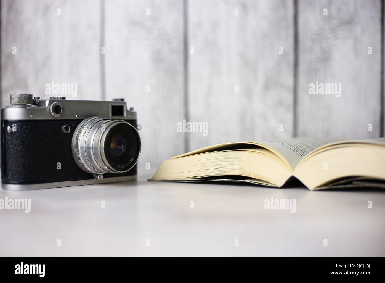 Vintage camera next to an open book on a light background Stock Photo ...
