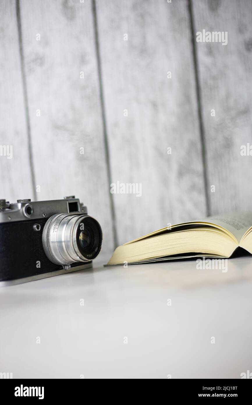 Vintage camera next to an open book on a light background Stock Photo ...
