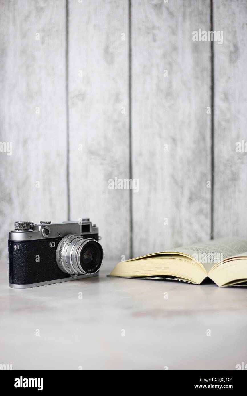 Vintage camera next to an open book on a light background Stock Photo ...