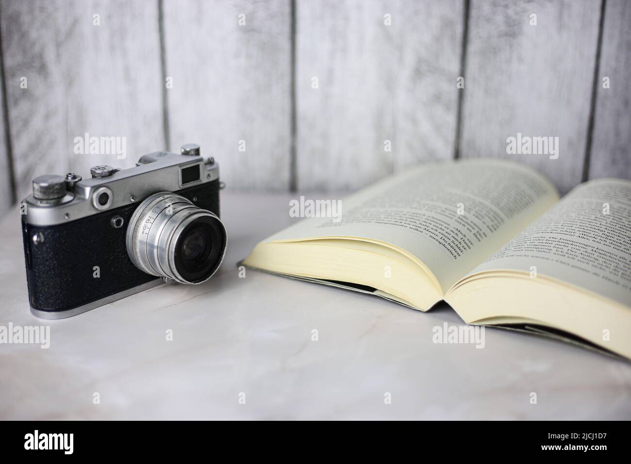 Vintage camera next to an open book on a light background Stock Photo ...