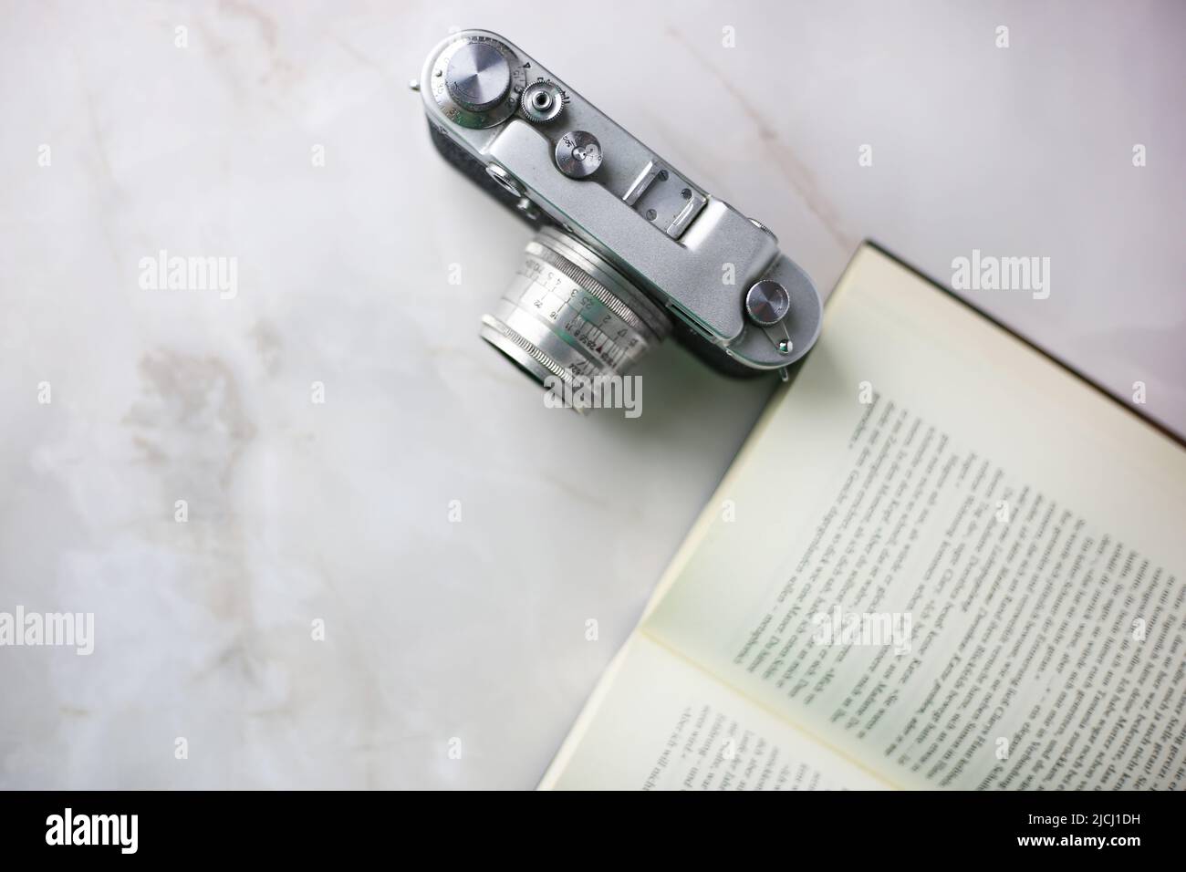 Vintage camera next to an open book on a light background Stock Photo ...