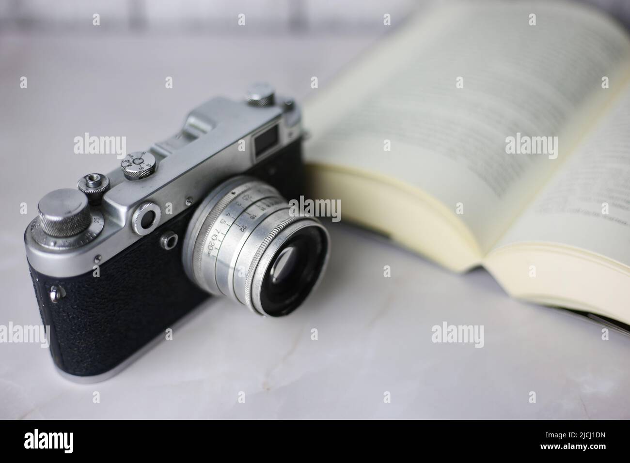 Vintage camera next to an open book on a light background Stock Photo ...