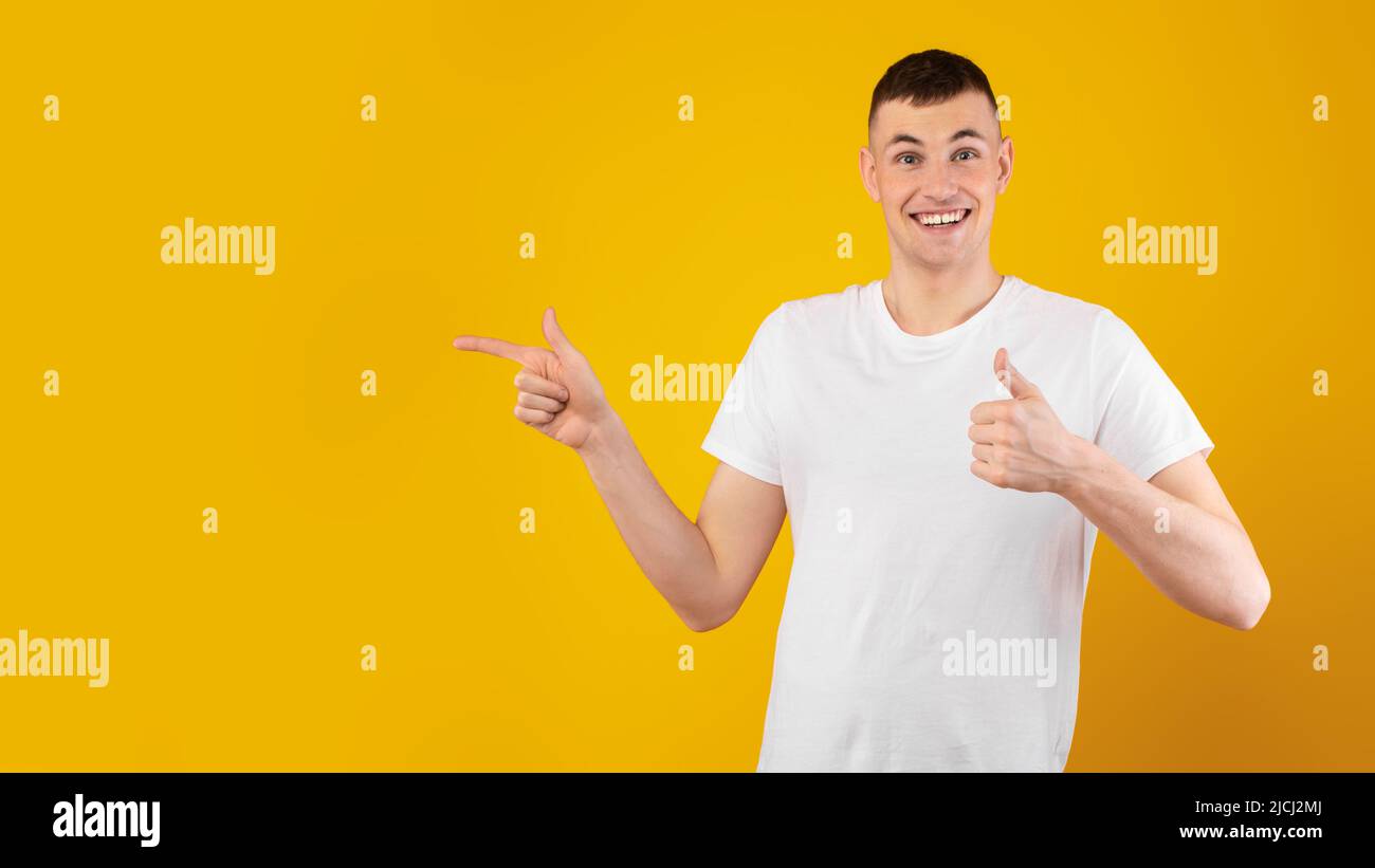Happy Guy Pointing Fingers Aside Gesturing Thumbs Up, Yellow Background ...