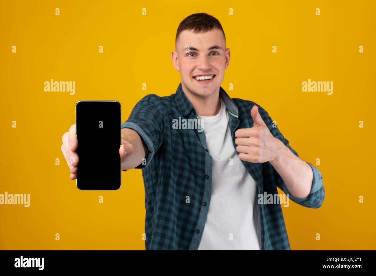 Cheerful Guy Showing Cellphone Gesturing Thumbs Up Over Yellow ...