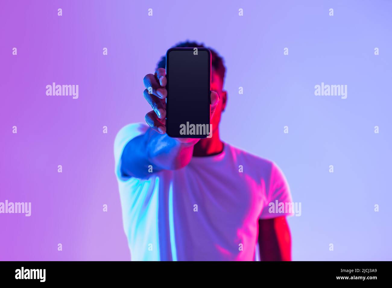 Young black guy holding cellphone with empty screen in front of his ...