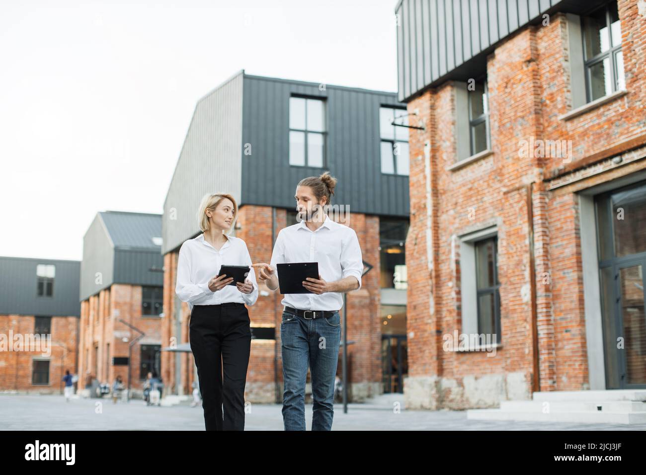 Smiling positiv woman in hijab carrying tablet while walking near ...
