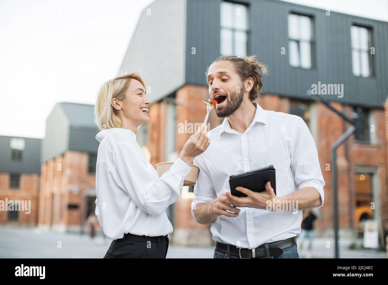 Two happy excited office workers walking together outdoors smiling and ...