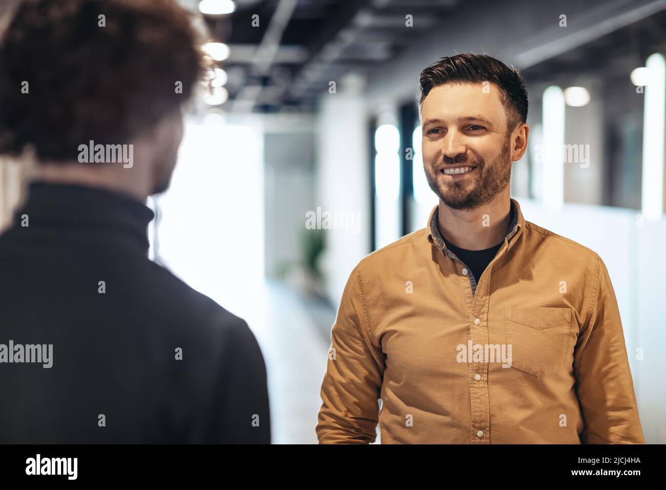 Business cooperation concept. Happy male colleagues standing face to ...