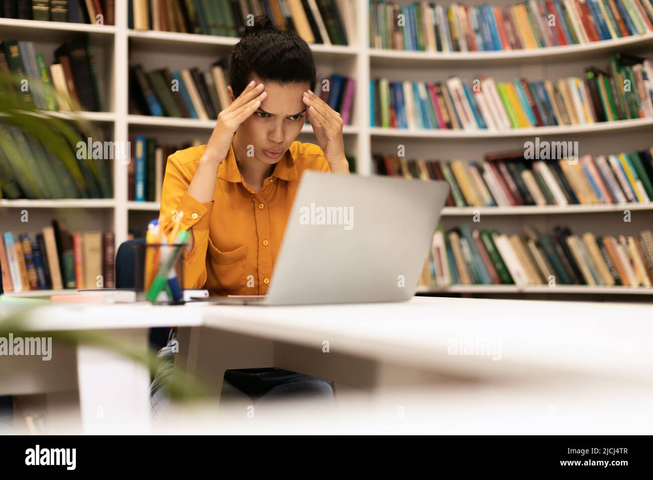 Thoughtful mixed race woman using laptop, working on computer in ...