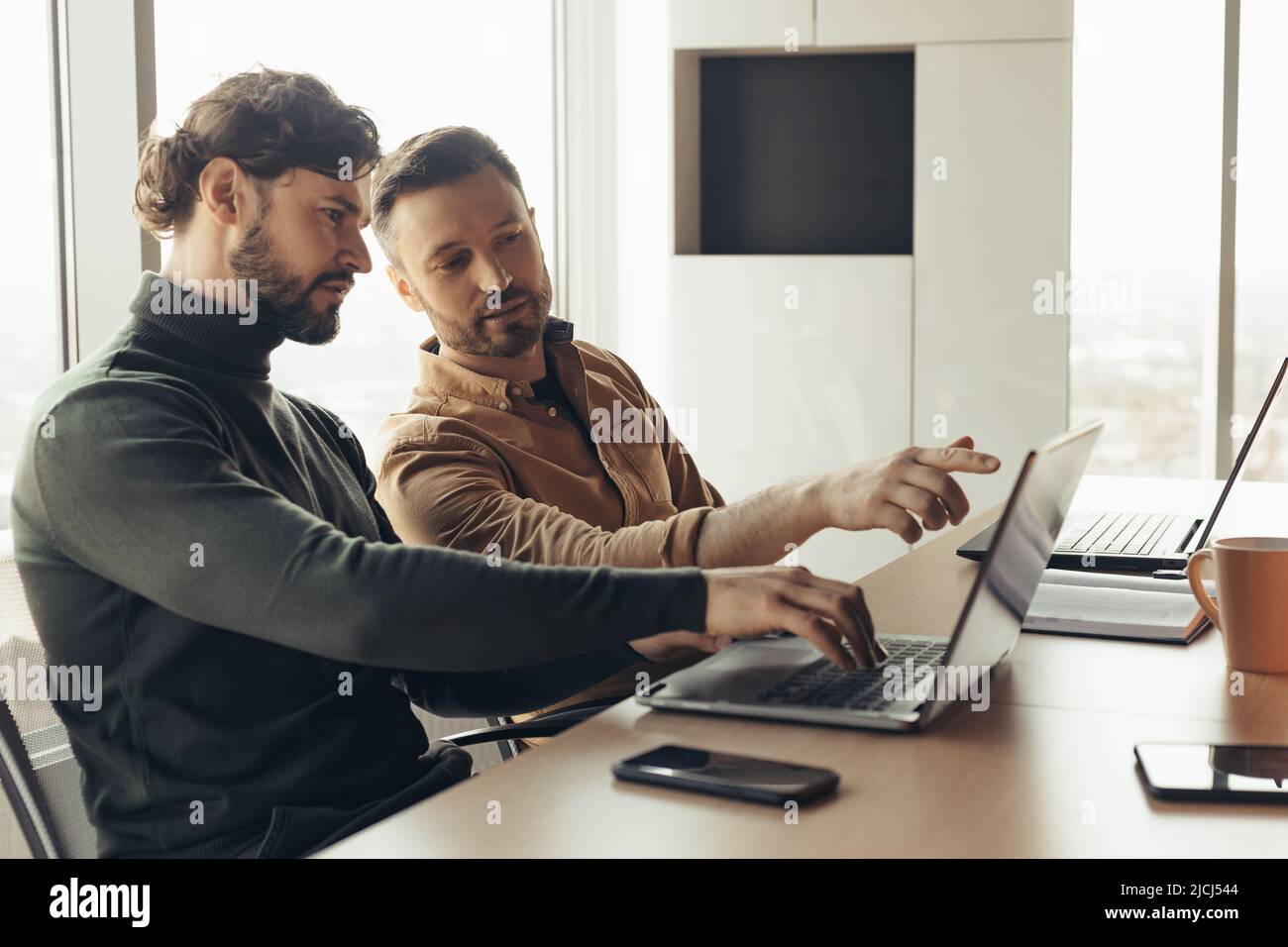 Teamwork and collaboration. Male coworkers communicating, using laptop ...