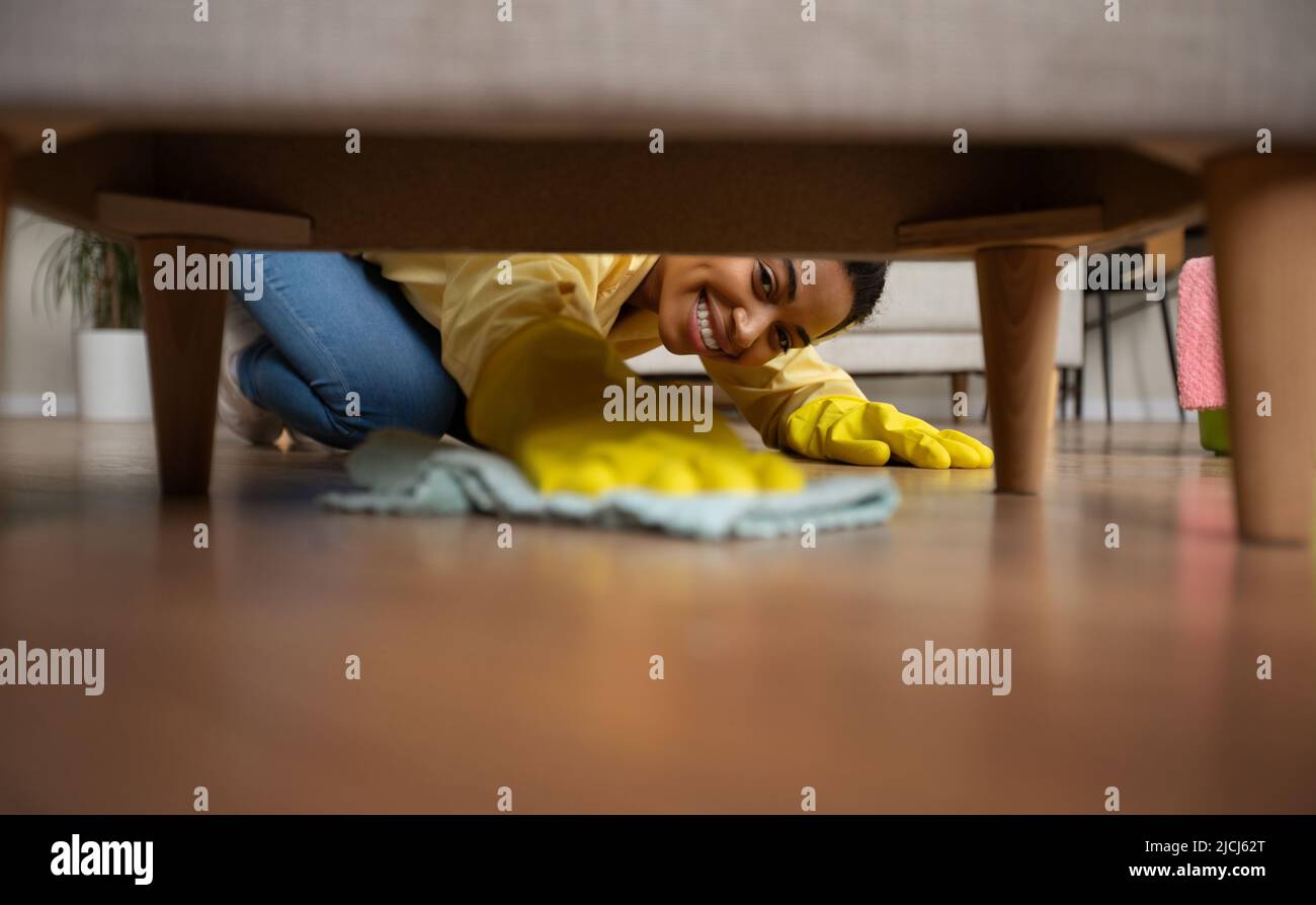 Joyful Black Woman Mopping And Dusting Floor Under Couch Indoor Stock ...