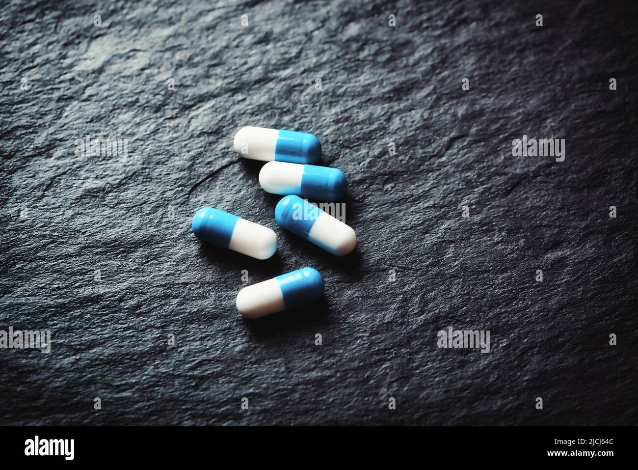 Sports Supplements (creatine capsules) on dark stone background. Close ...