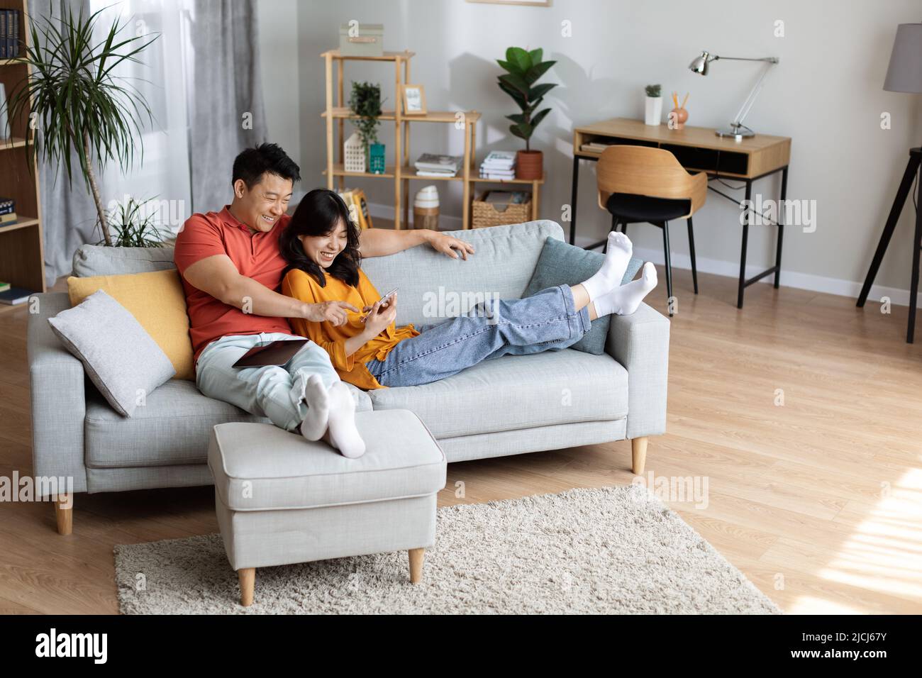 Relaxed japanese couple chilling together at home, using gadgets Stock ...