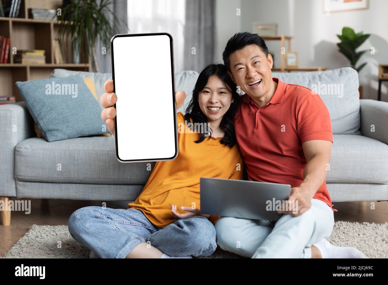 Happy asian couple chilling together at home, using gadgets Stock Photo ...