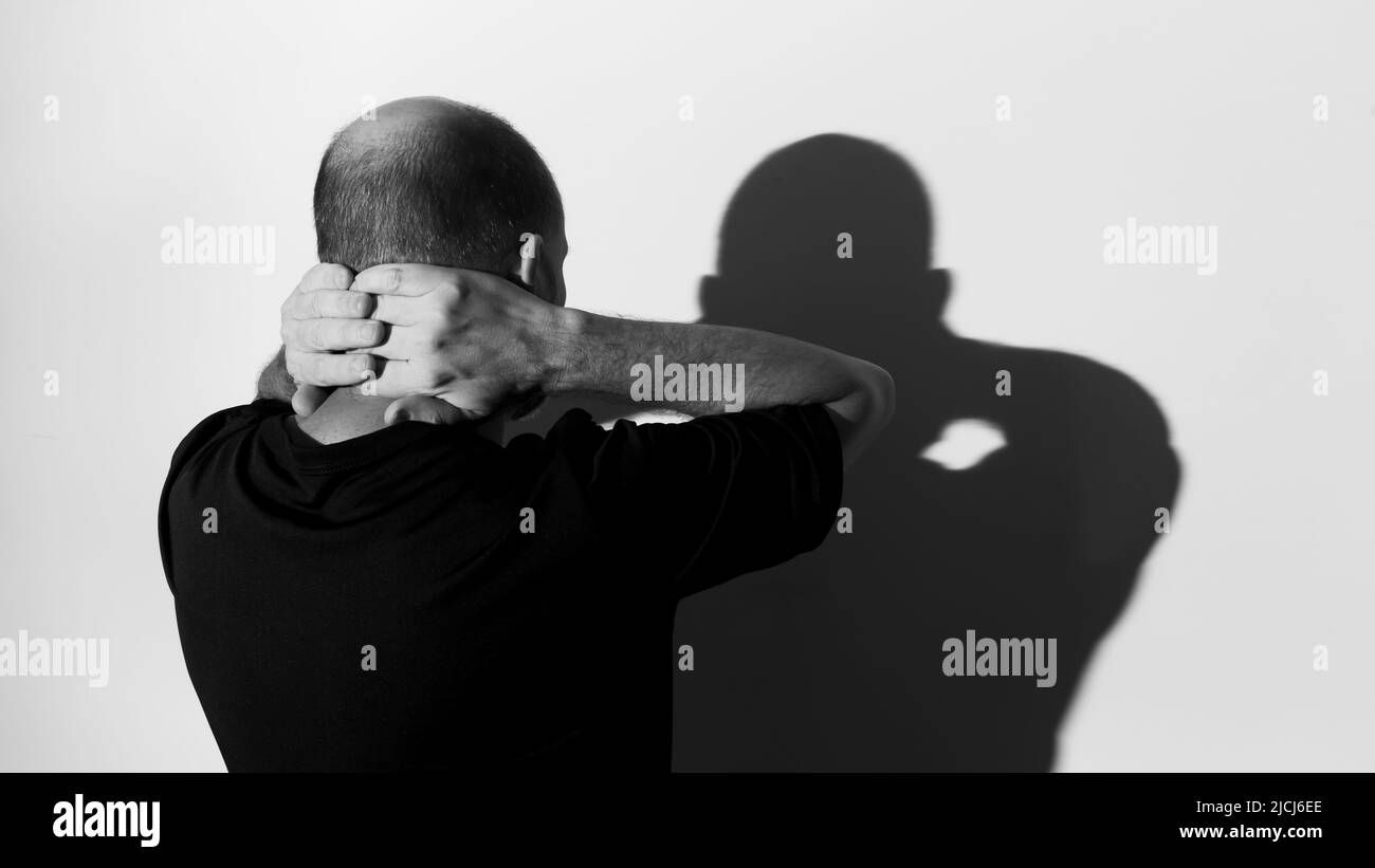 Portrait of a man and his shadow against white wall background ...