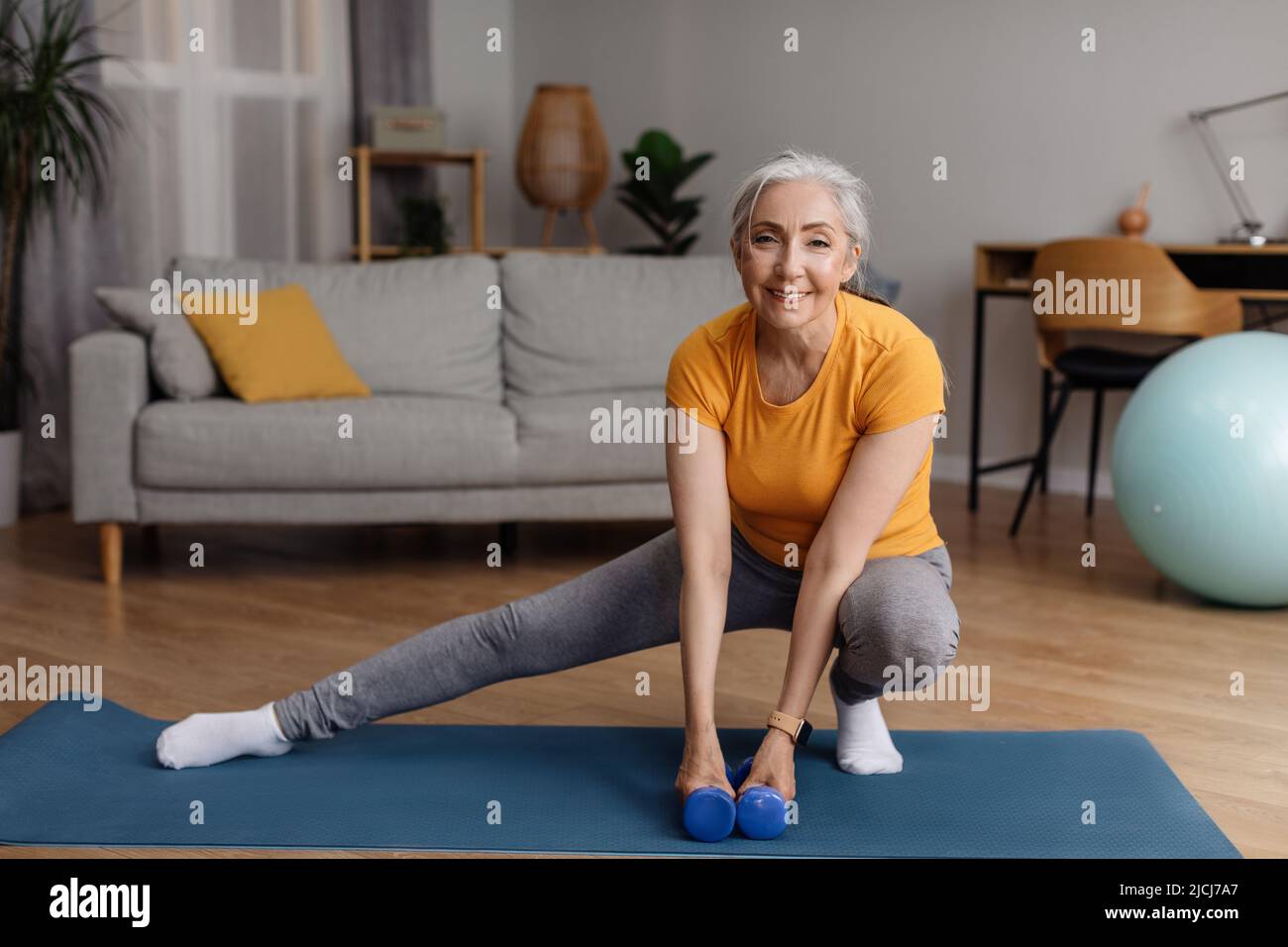 Happy senior woman warming up, doing legs stretching exercises while ...