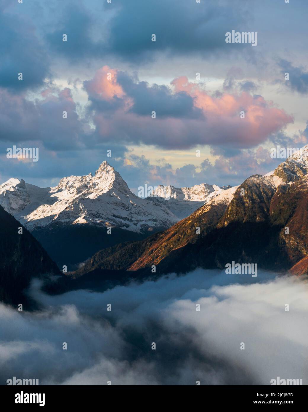 sharp mountain peak under beautiful sky and fog over valley from below ...