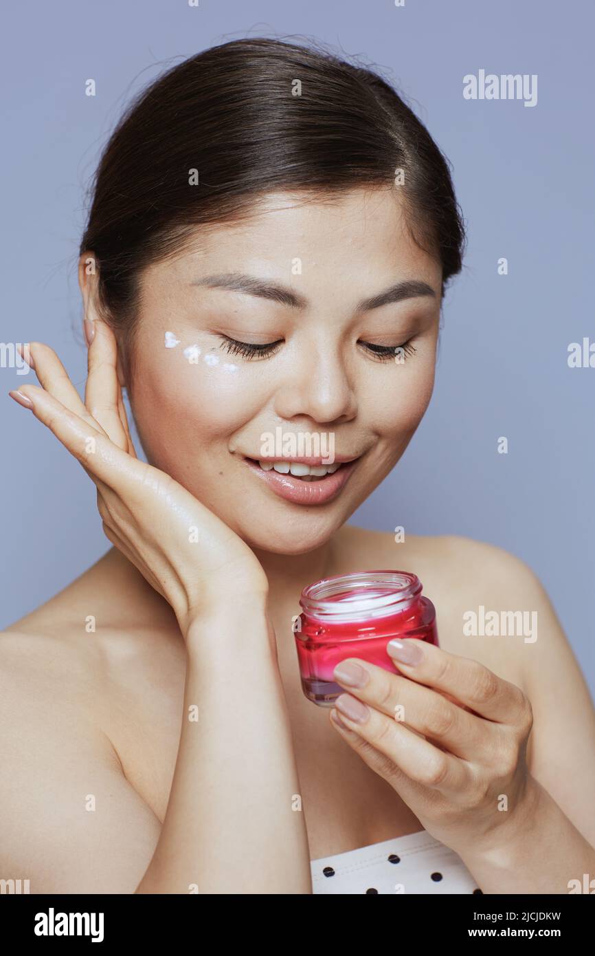 modern woman with facial cream jar and facial cream on face against ...