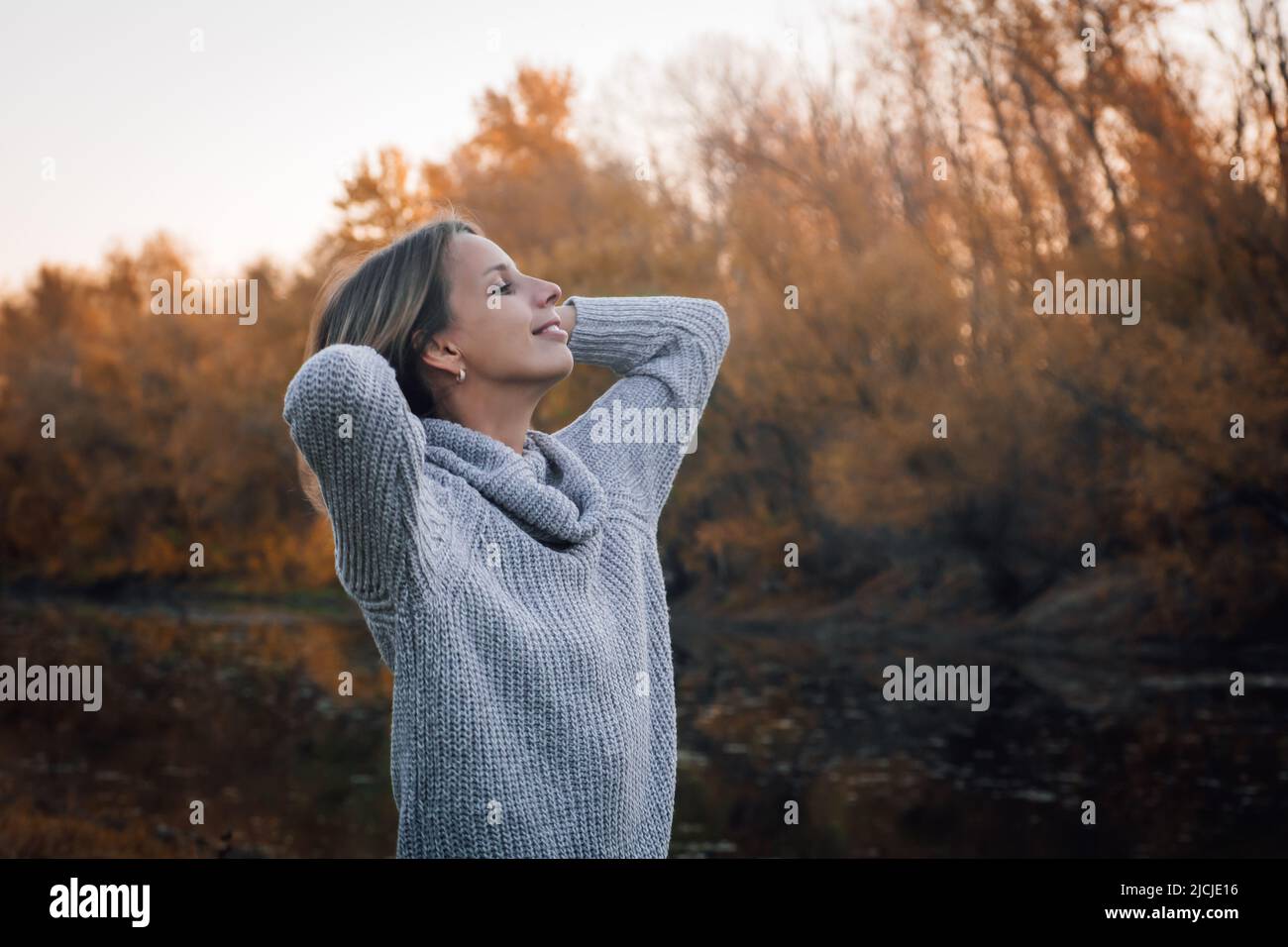 Close-up of young blonde Caucasian woman standing in forest, looking ...