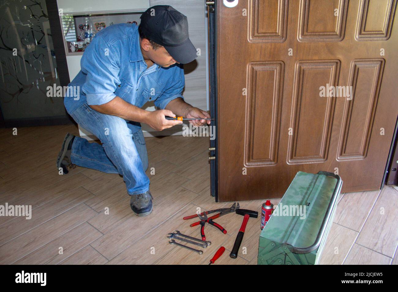 Picture of a handyman who repairs the lock of the house door with his ...
