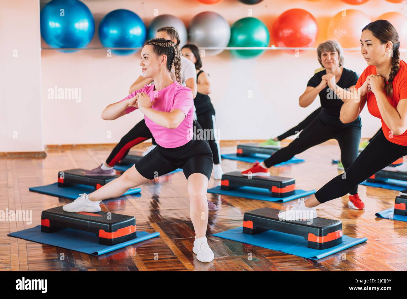 Group of women doing step aerobics doing leg stretching Stock Photo - Alamy