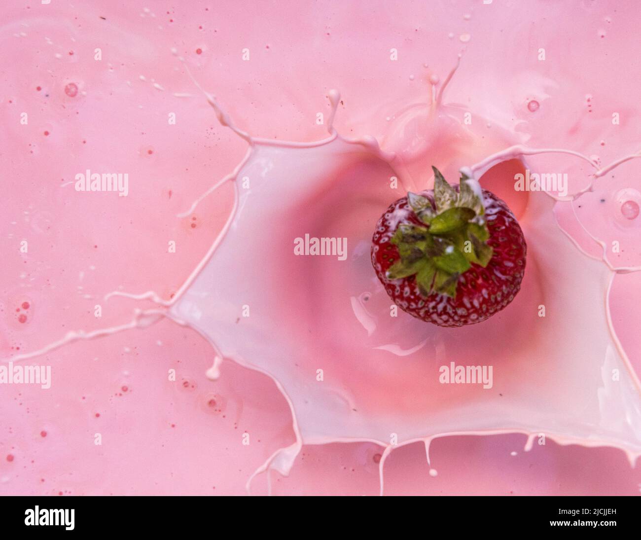 Action image of a strawberry splashing into a bowl of pink cream Stock ...