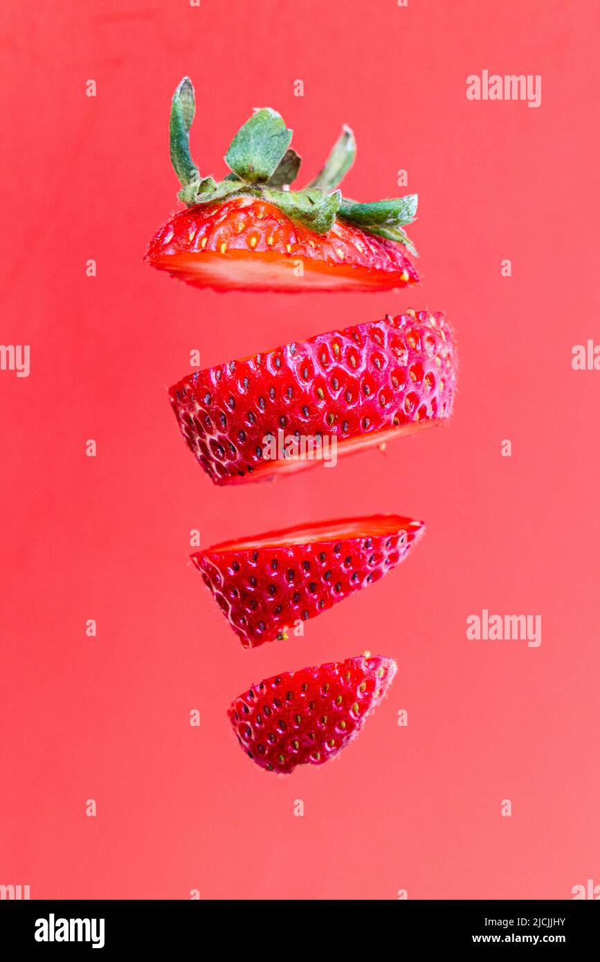 Close up of a sliced strawberry floating over a red background Stock ...